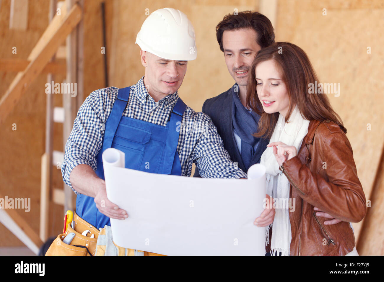 foreman shows house design plans to a young couple Stock Photo - Alamy