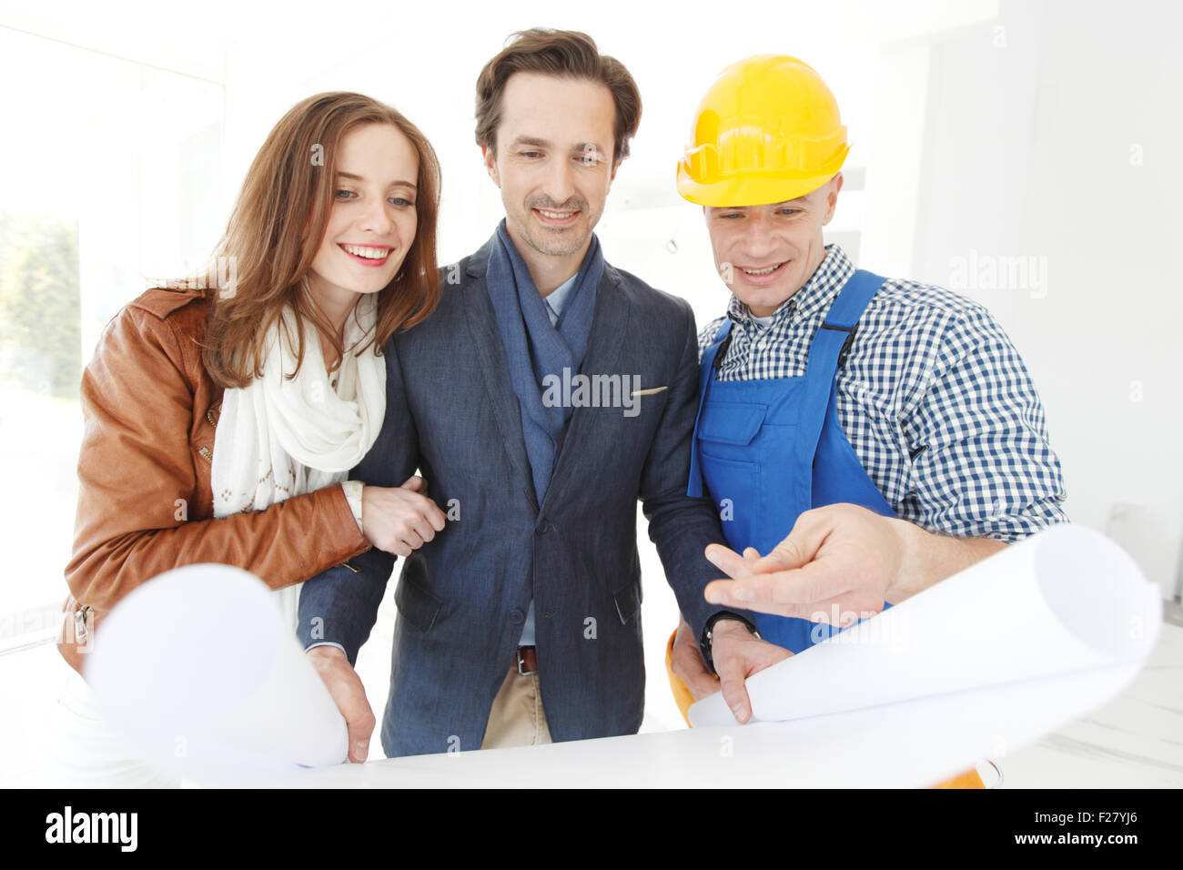 foreman shows house design plans to a young couple Stock Photo - Alamy