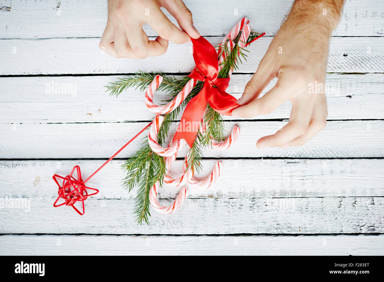 Human hands binding Christmas bouquet made up of candy canes, red star ...