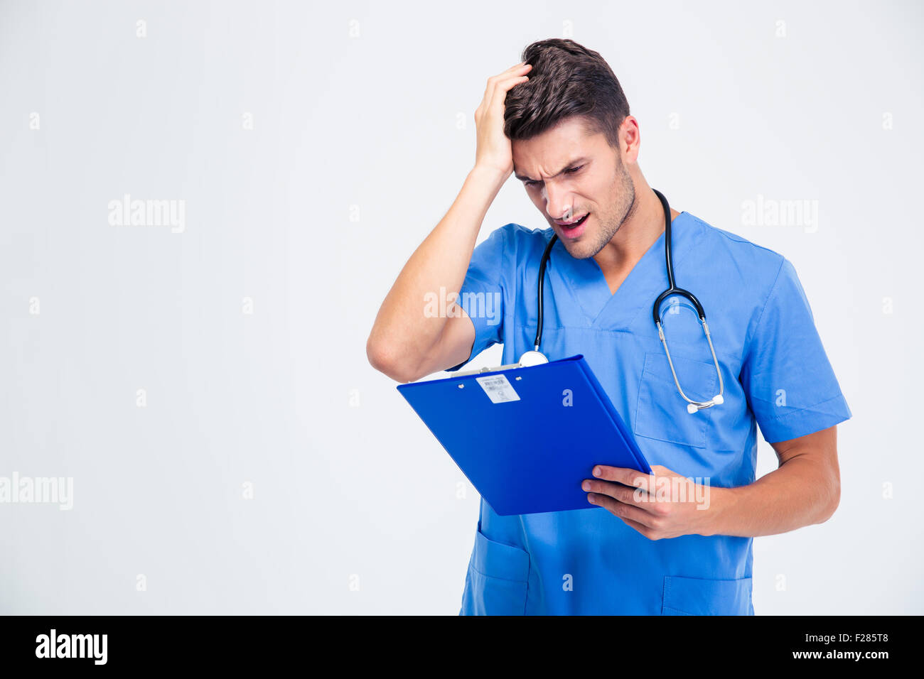 Portrait of a disappointed male doctor standing with clipboard isolated ...