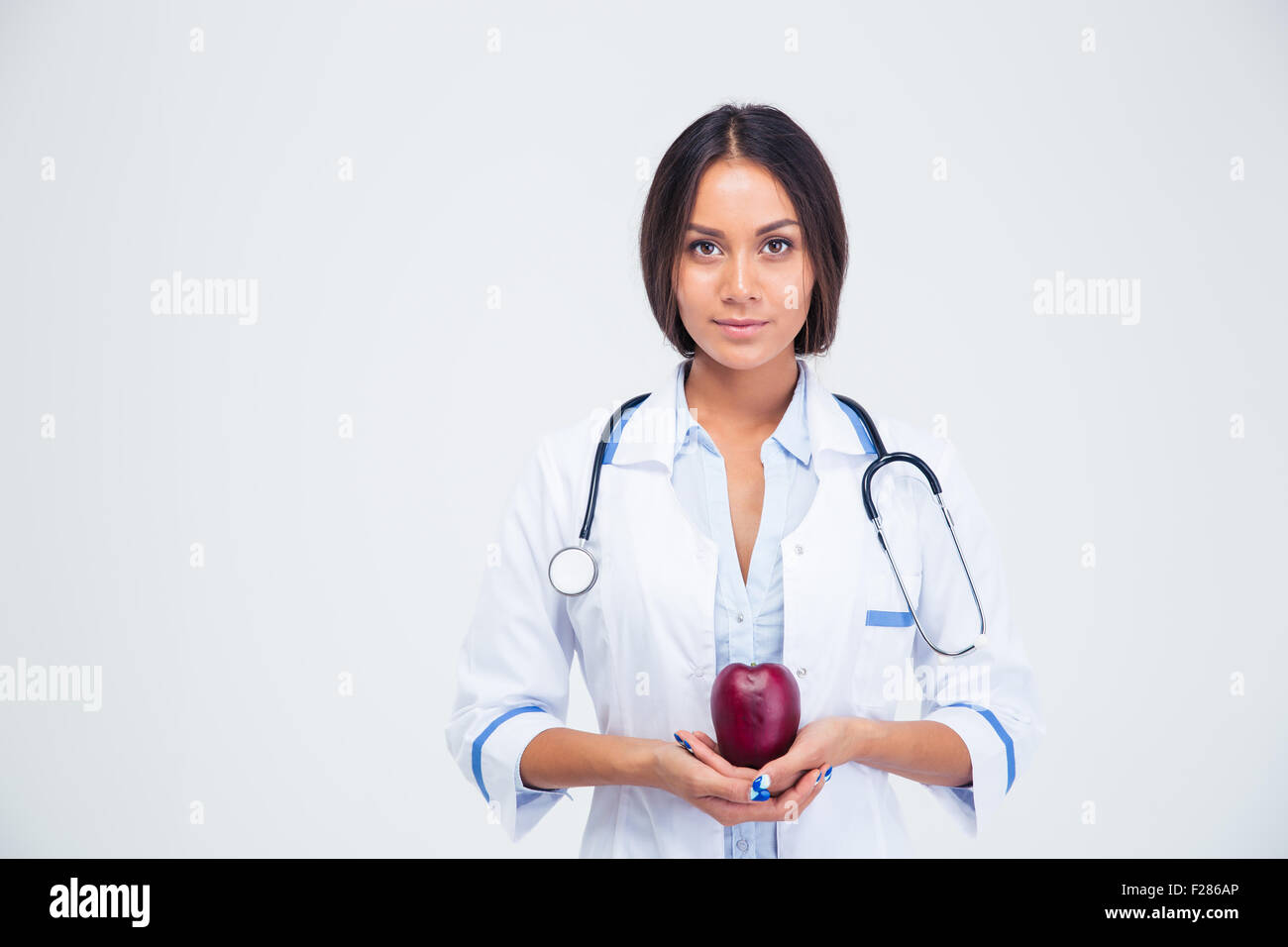 Portrait of pretty female doctor holding apple isolated on a white ...