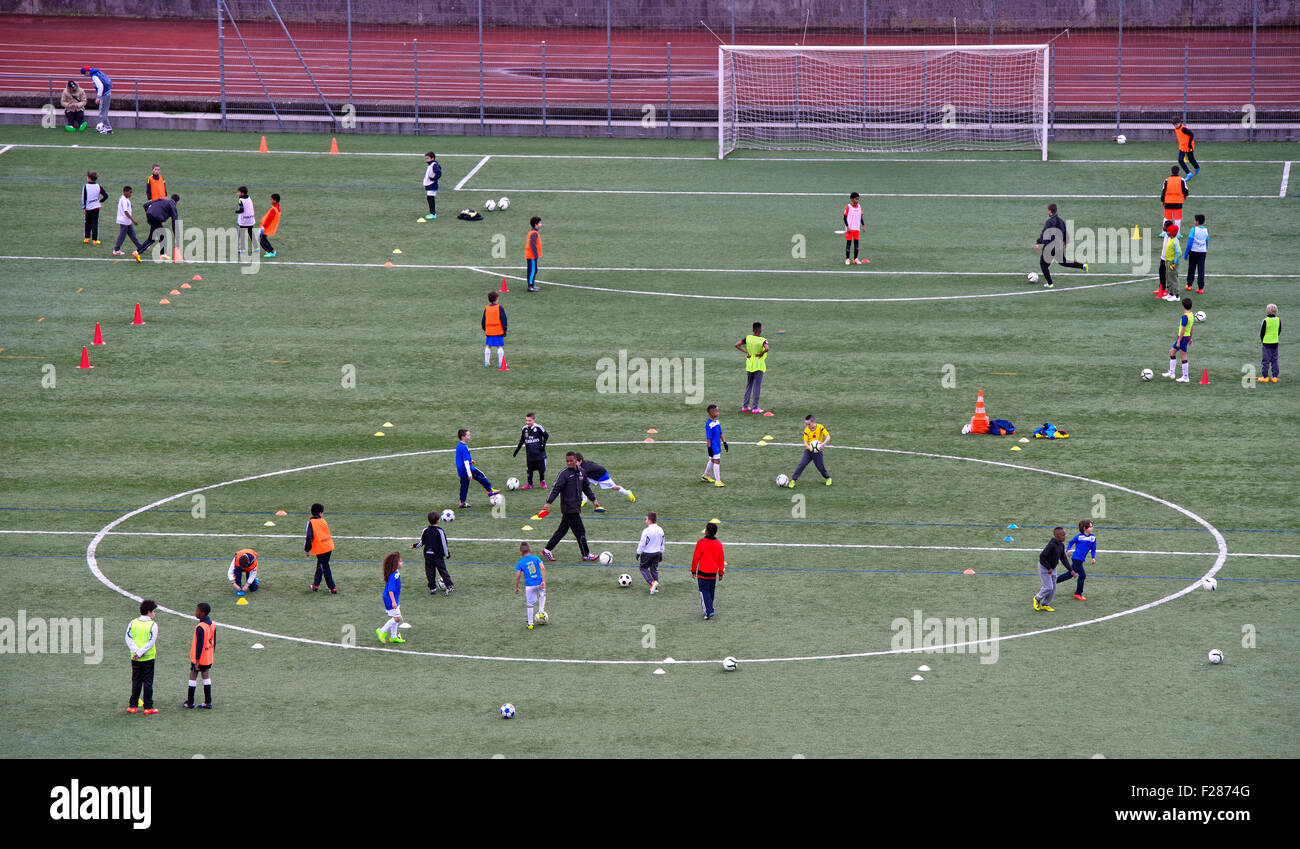 Children in colorful clothes on a sports field, during soccer practice ...