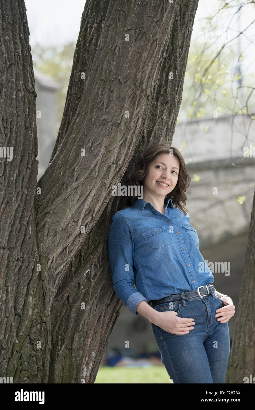 Mature woman leaning against tree in park, Bavaria, Germany Stock Photo ...