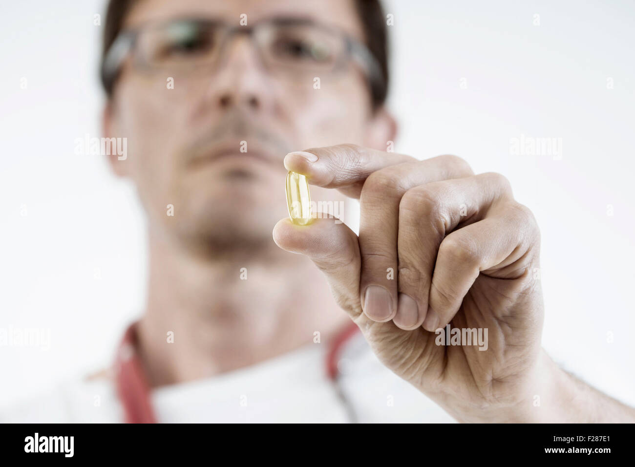 Male doctor showing a capsule of dietary supplement, Bavaria, Germany ...