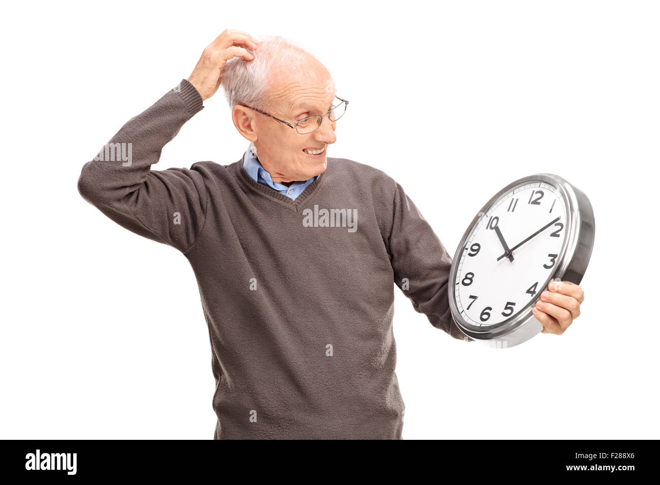 Confused senior holding a big wall clock and scratching his head ...