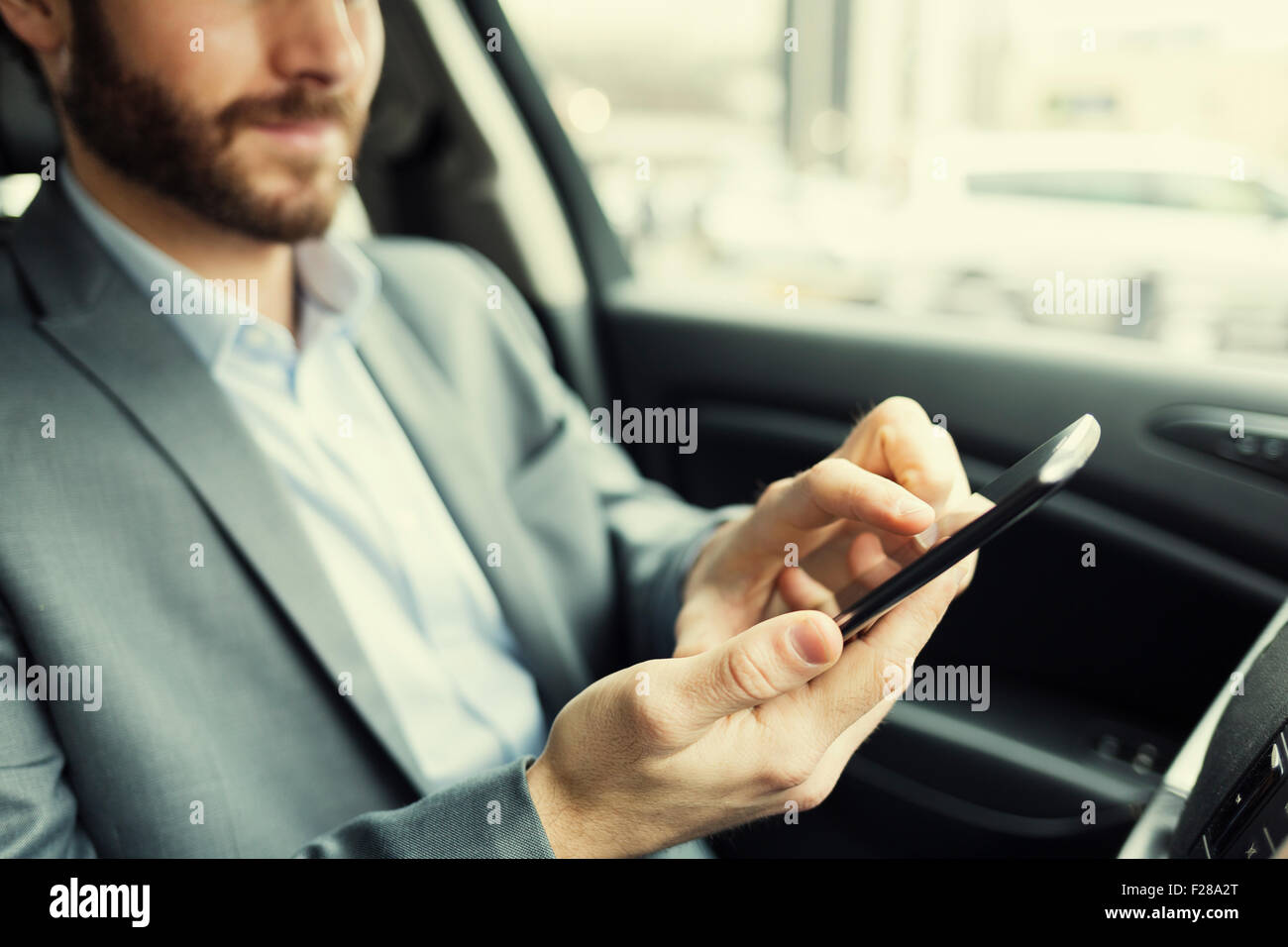 Man in car. Typing text message on mobile phone Stock Photo - Alamy