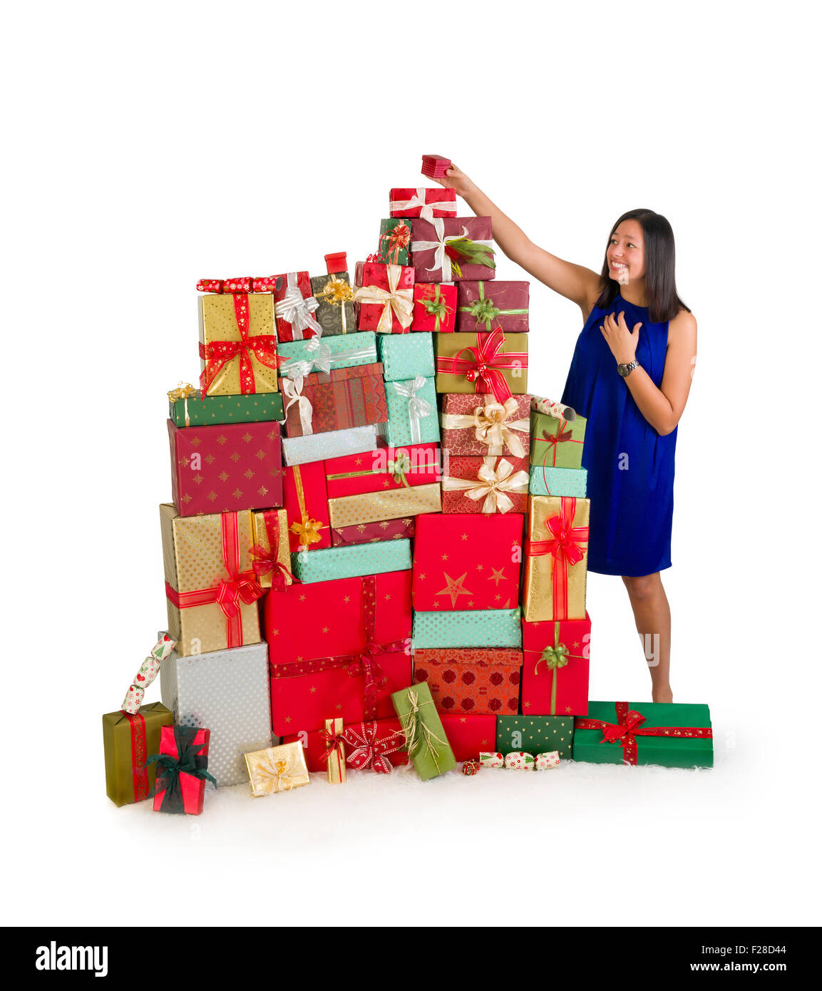 Young woman putting one little gift on top of a huge stack of christmas ...