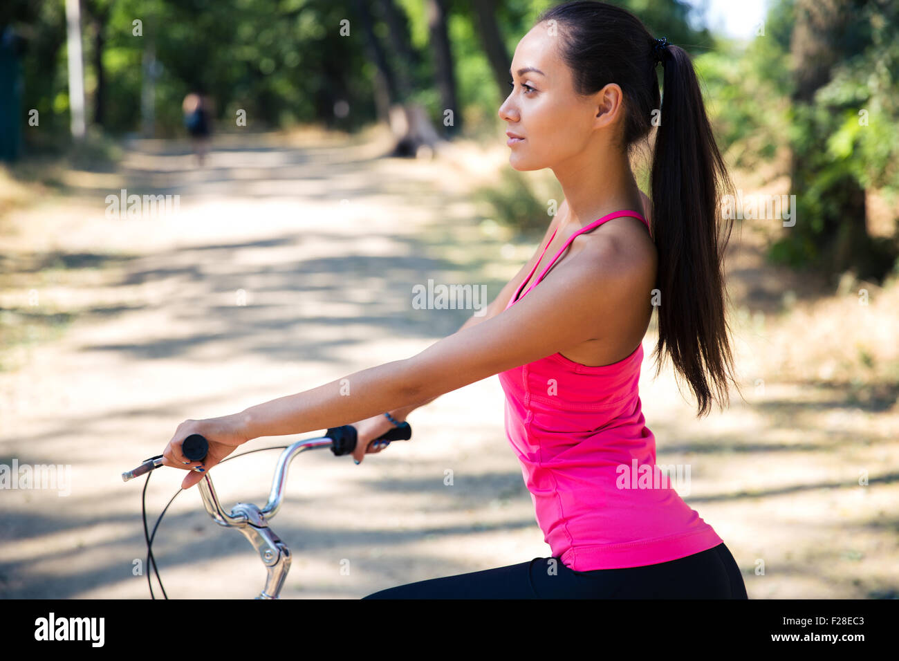 Portrait of a charming woman riding on bicycle in park Stock Photo - Alamy