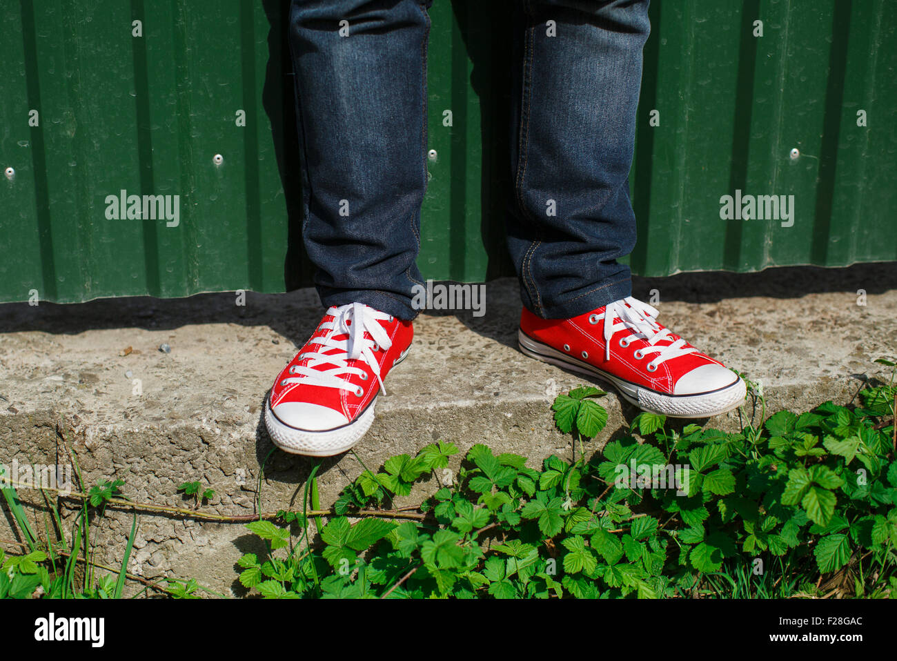 Red sneakers shoes on concrete against the background of the fence ...