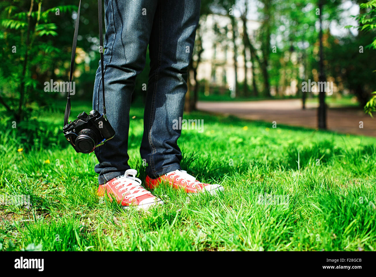 Traveler with old photo camera standing on the grass. View of legs ...