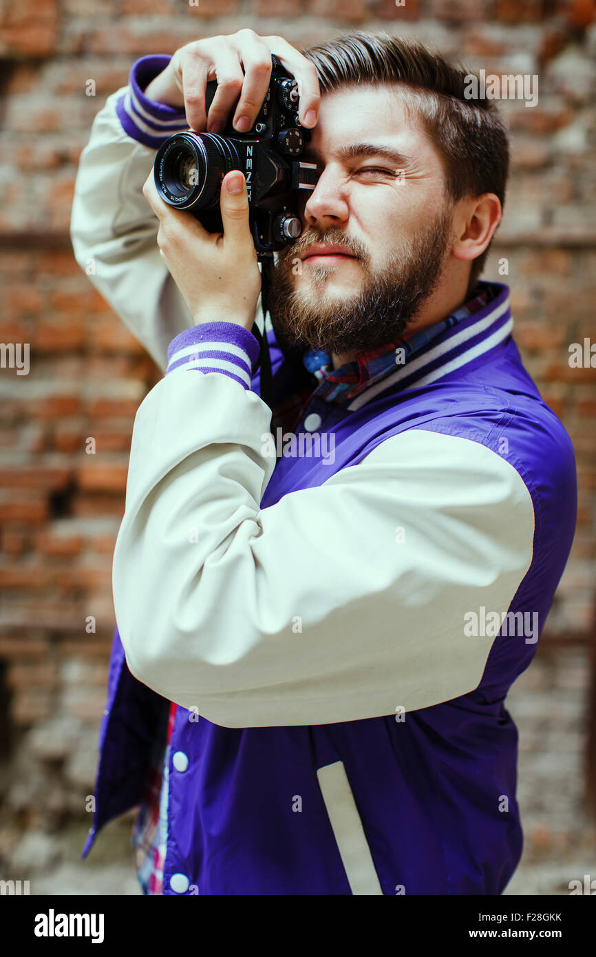 Young man with old film photo camera taking a photo outdoor, hipster ...
