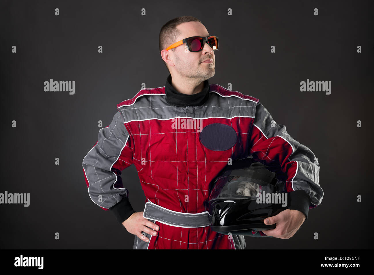 Racing driver posing with helmet isolated in black Stock Photo - Alamy
