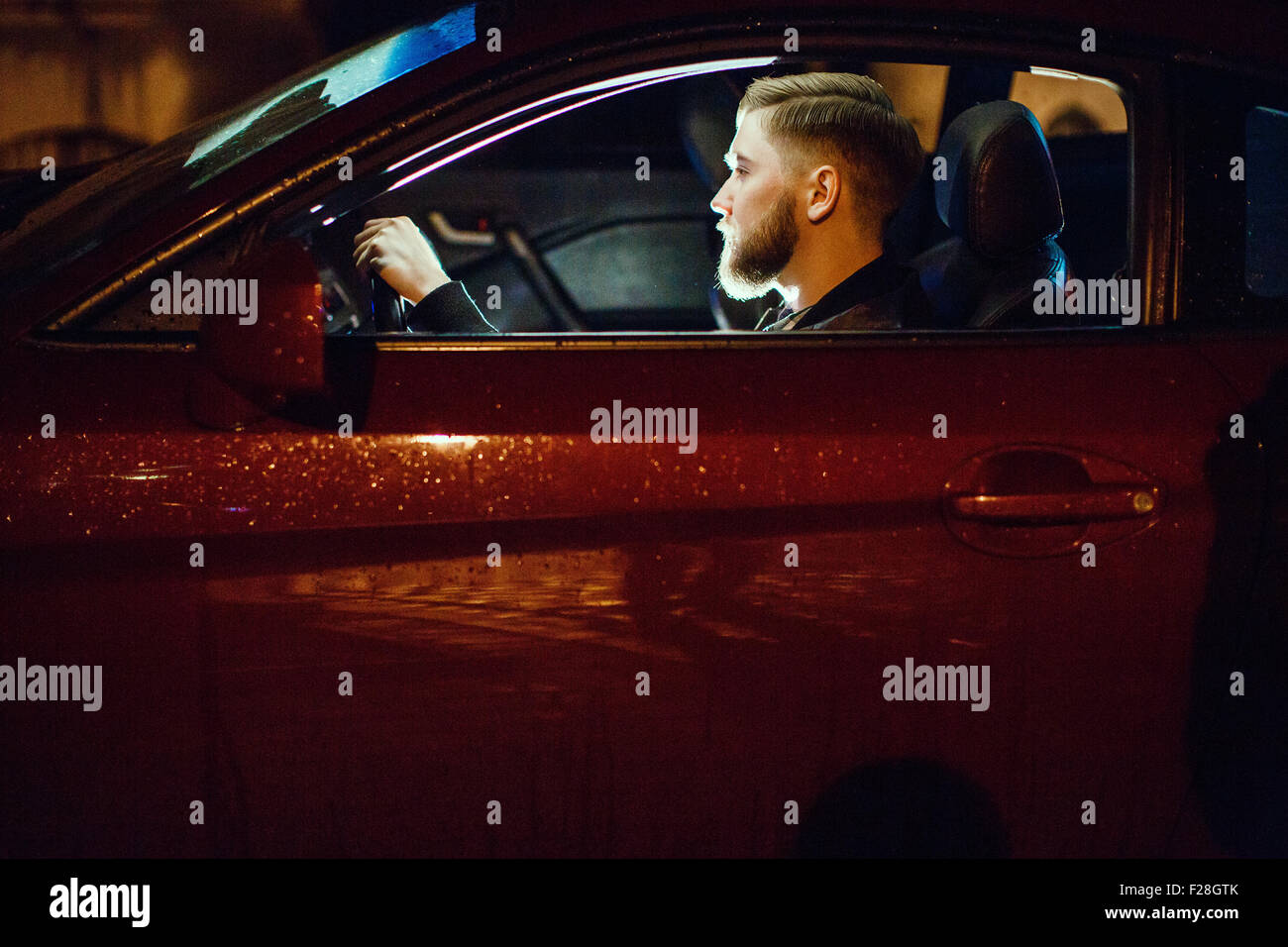 Handsome bearded man driving his sport car, at night, in profile Stock ...