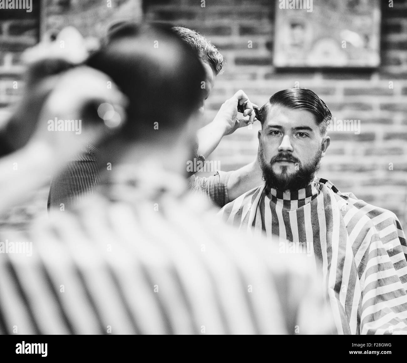 Barber cutting bearded brutal man, reflection in the mirror, black and ...