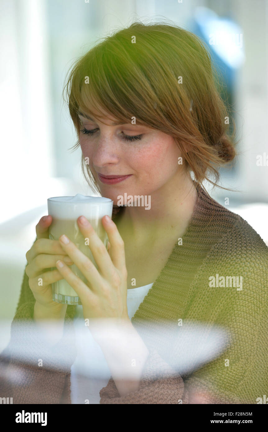 A woman is drinking a latte macchiato Stock Photo - Alamy