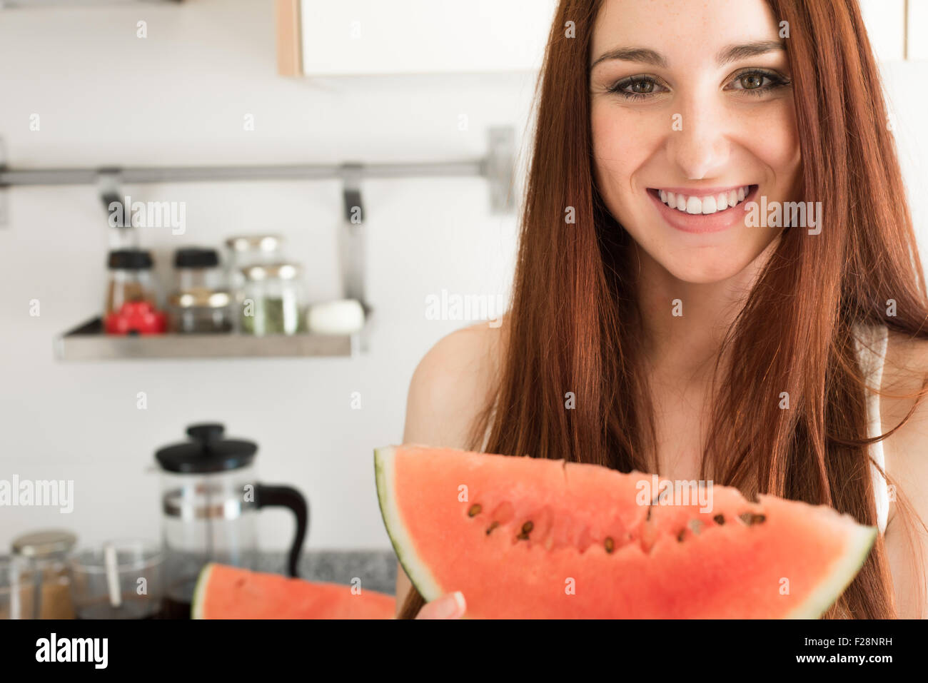 Young woman eating watermelon in the kitchen Stock Photo - Alamy