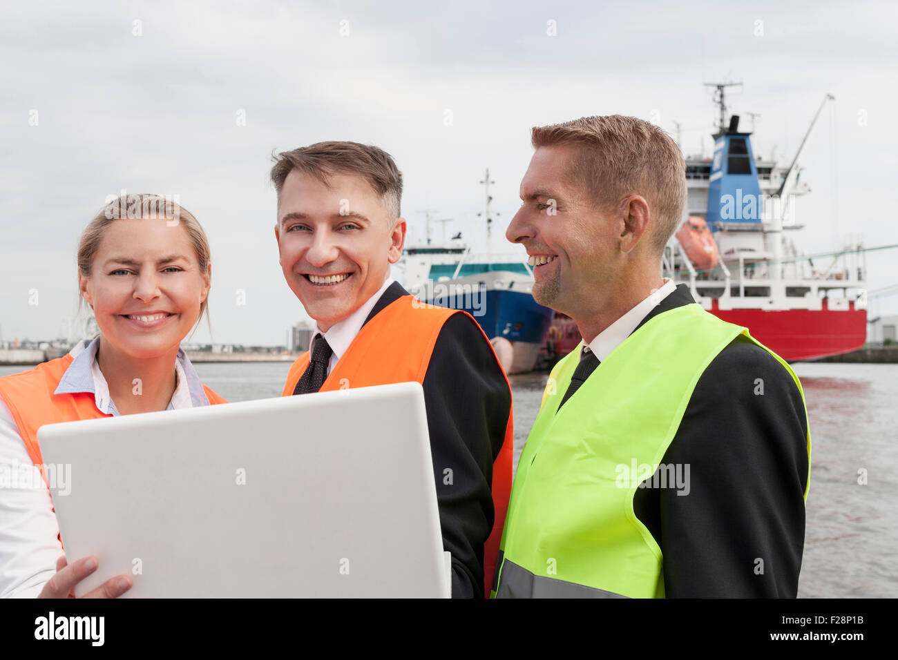 Portrait of business people working on laptop at harbour, Hamburg ...