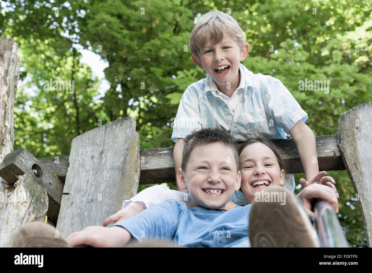 Three friends having fun on slide in playground, Munich, Bavaria ...