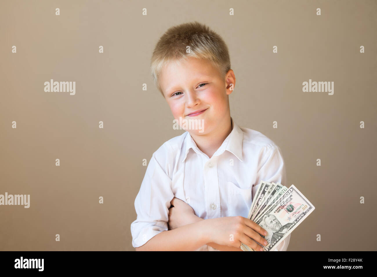 Happy smiling child with money (dollars) in hand on grey background ...