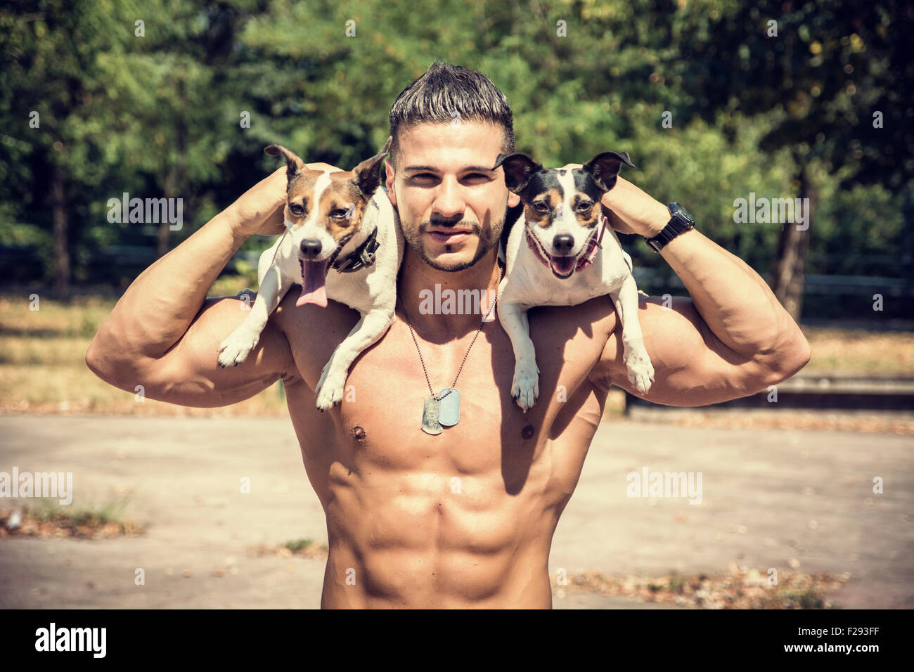 Half Body Shot of a Shirtless Athletic Young Man Carrying Two Dogs on ...