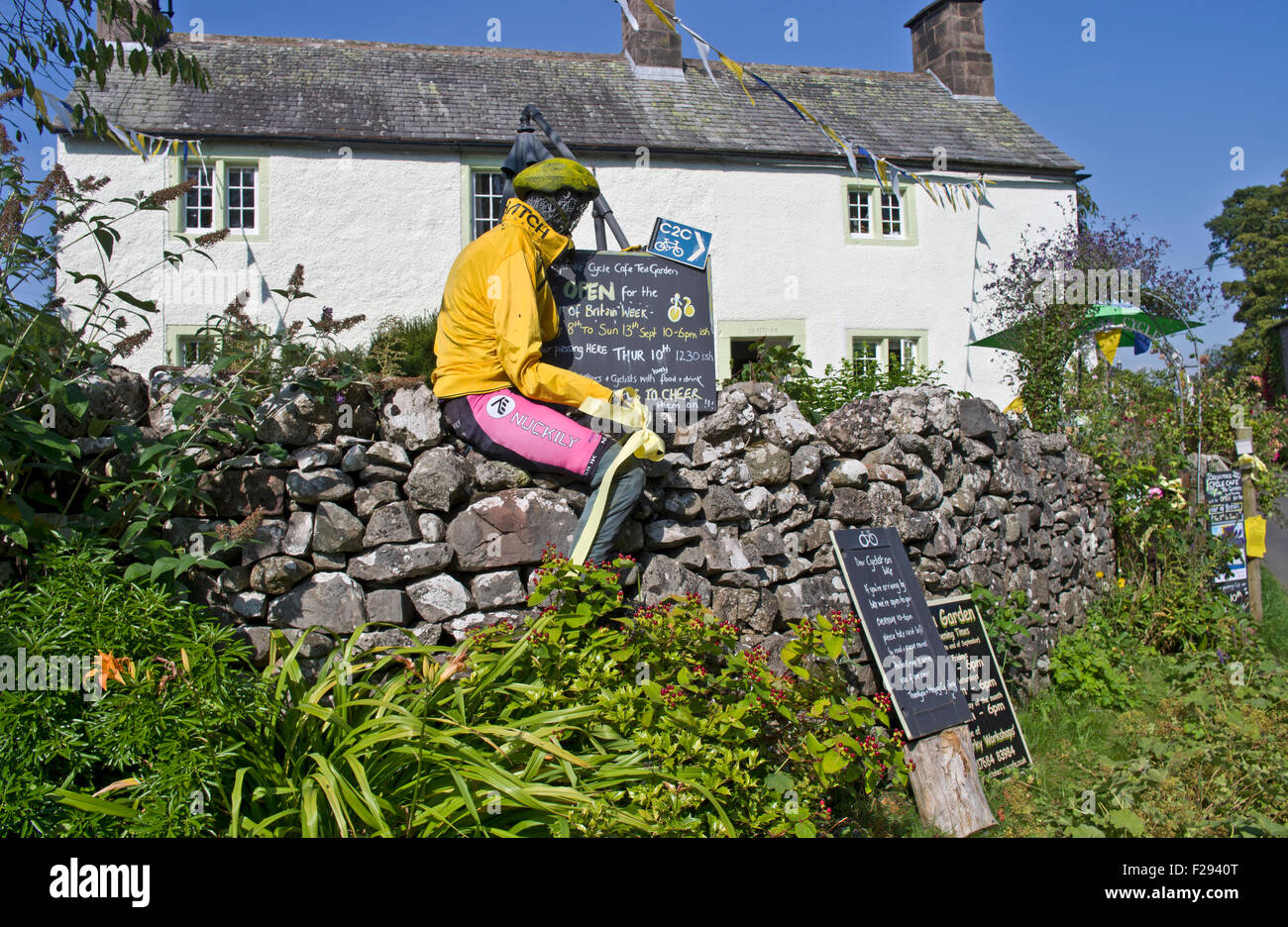 Lifesize model of cyclist wearing yellow jersey on dry stone wall ...