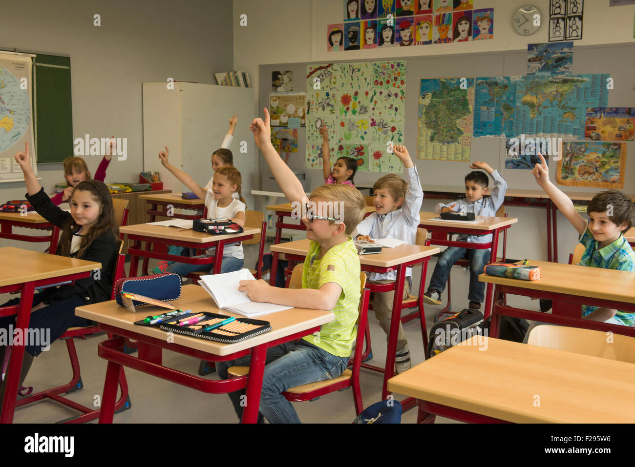 school children with raised hands in classroom, Munich, Bavaria ...