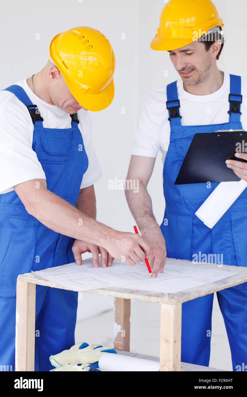 Two workers correcting a construction plan Stock Photo - Alamy