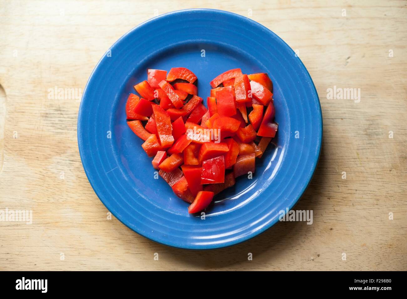 Chopped red peppers in a heart shape on a blue plate Stock Photo - Alamy