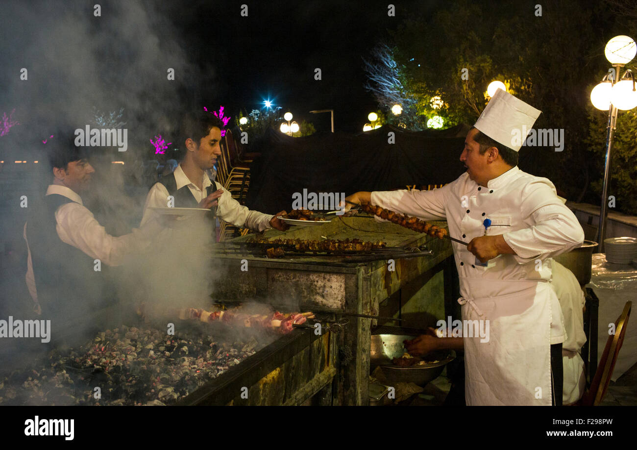 A chef pulls barbecued chicken off of skewers during a dinner at the ...