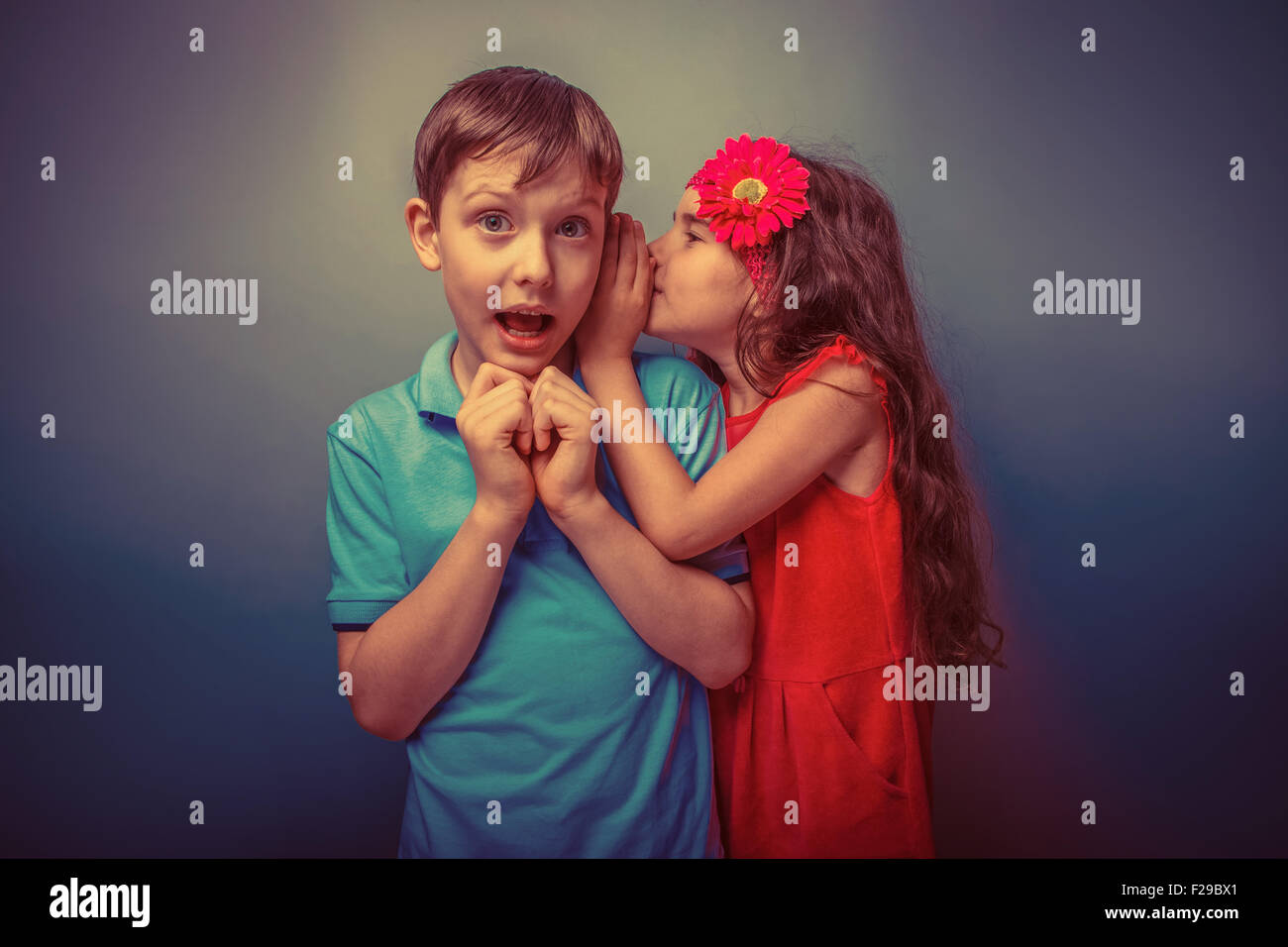 Teenage girl whispering in the ear of a secret teen boys on a g Stock ...