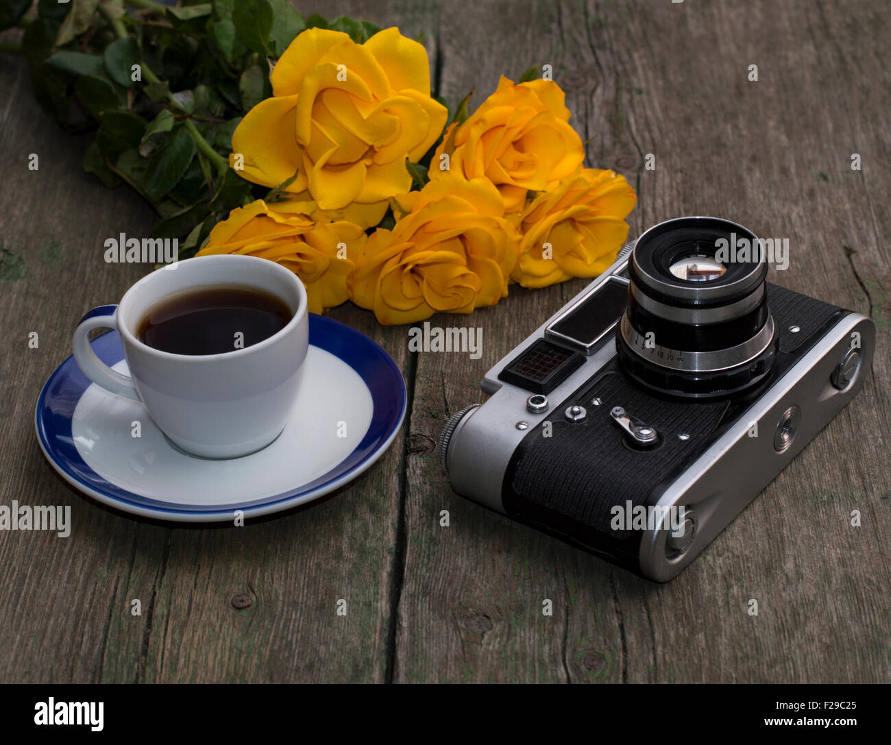 the ancient film camera, bouquet and coffee on an old wooden table, a ...