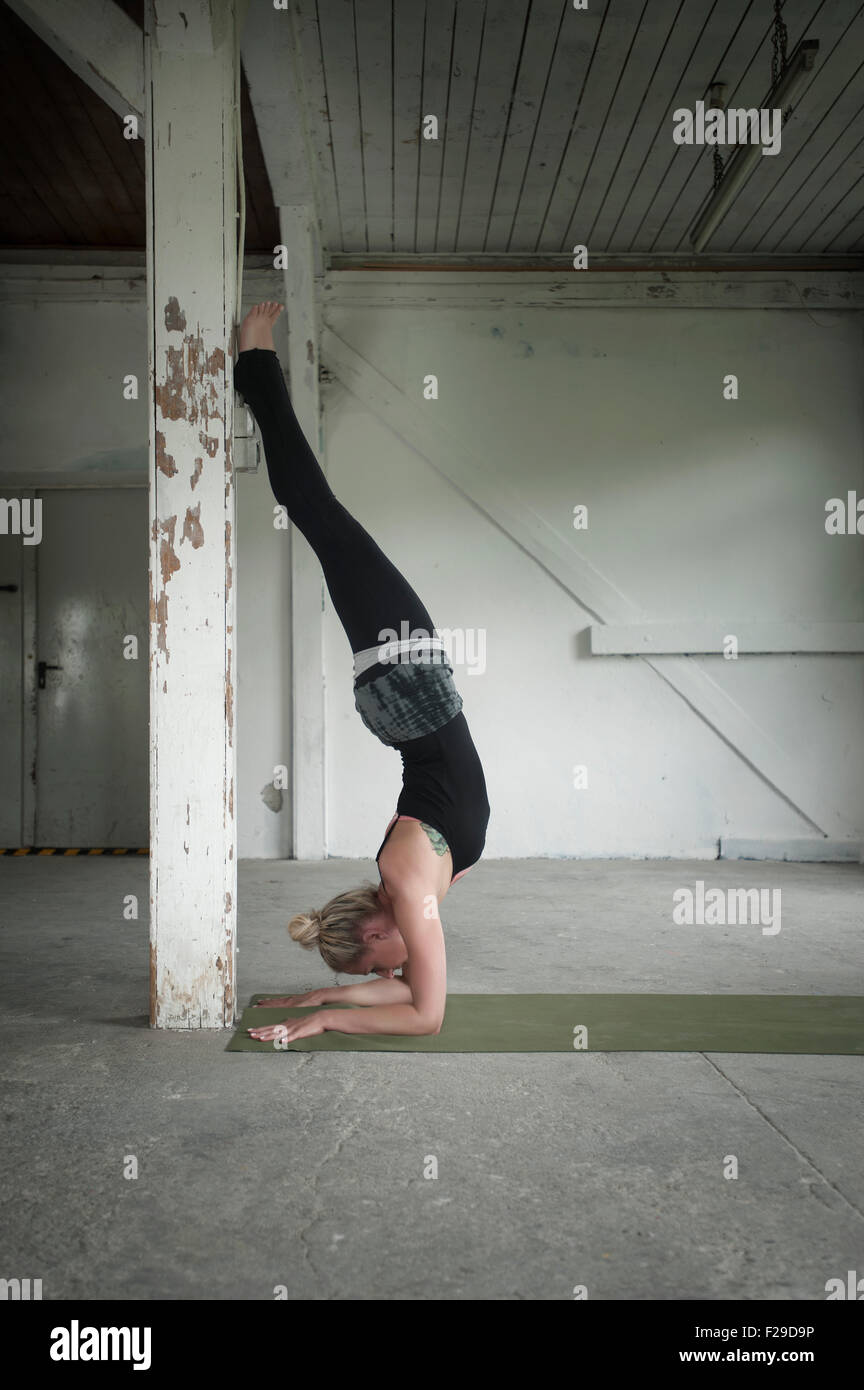 Mid adult woman practicing handstand in yoga studio, Munich, Bavaria ...