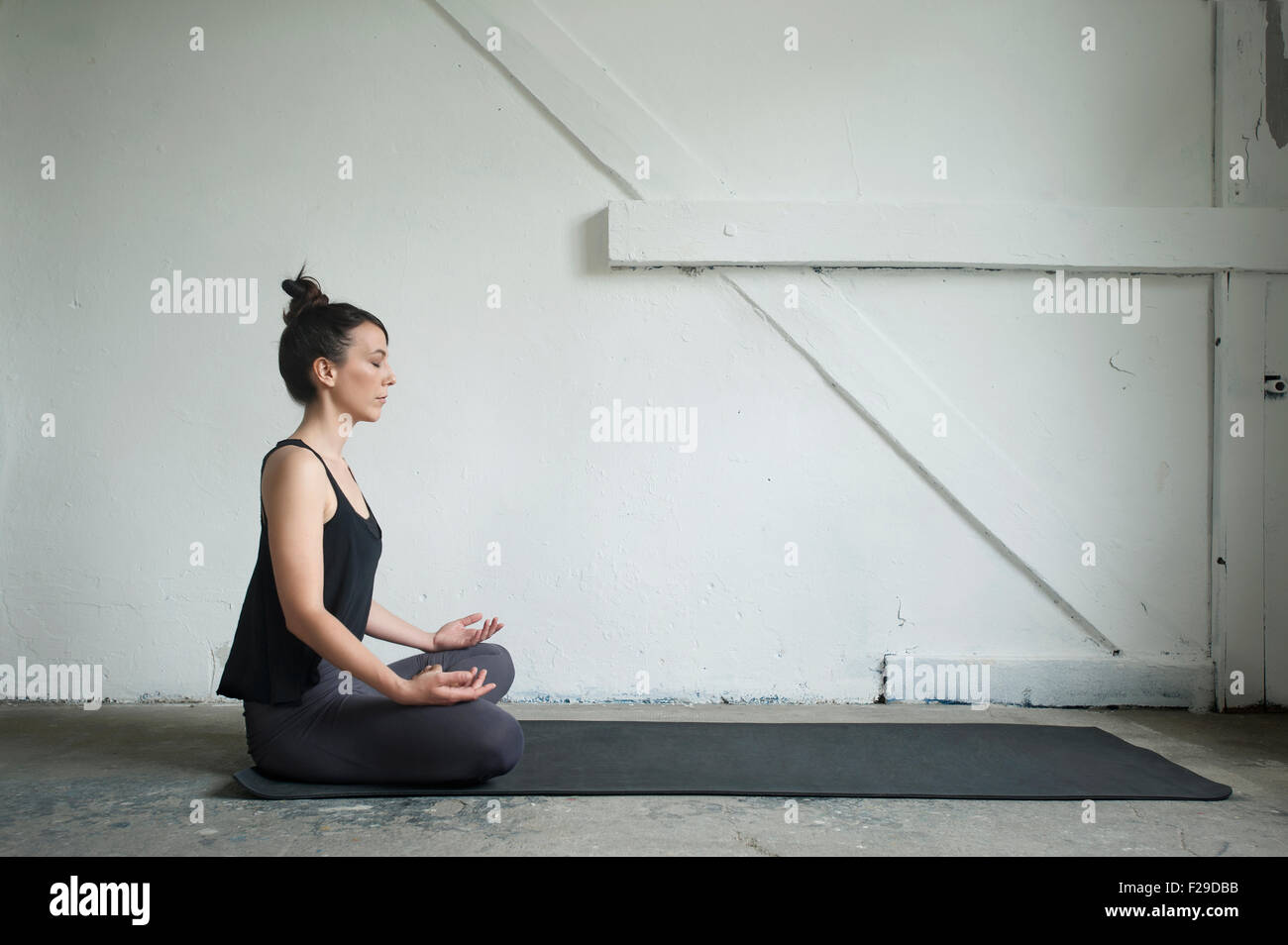 Side profile of a mid adult woman practicing lotus pose in yoga studio ...