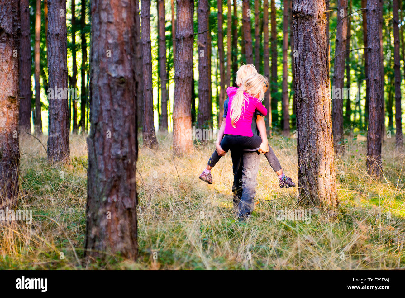 Young boy giving young girl piggyback outdoors smiling, forest ...