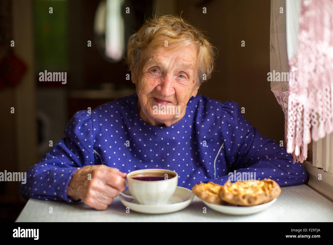 Old happy woman drinking tea in her kitchen Stock Photo - Alamy