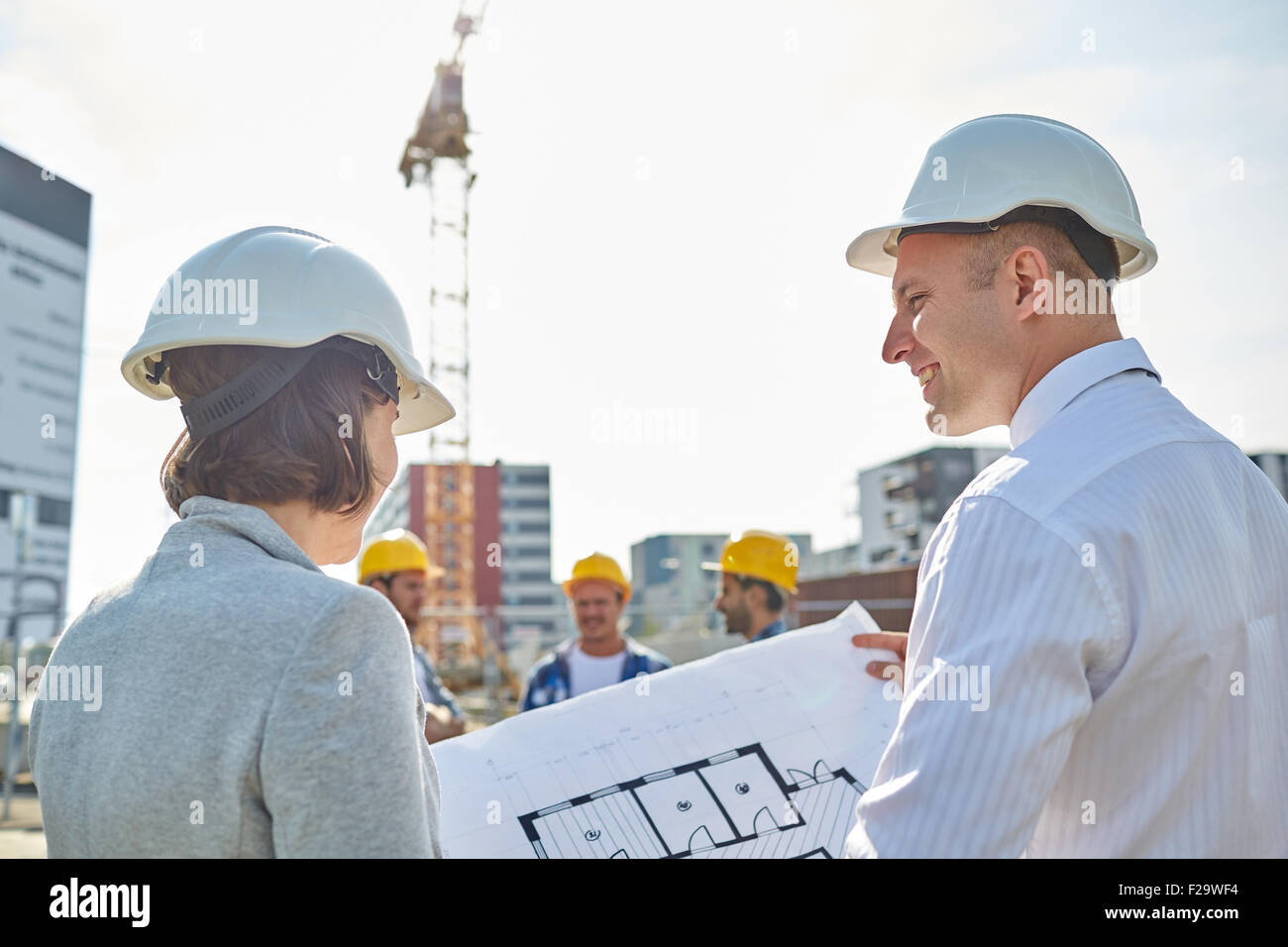 happy architects with blueprint at building Stock Photo - Alamy