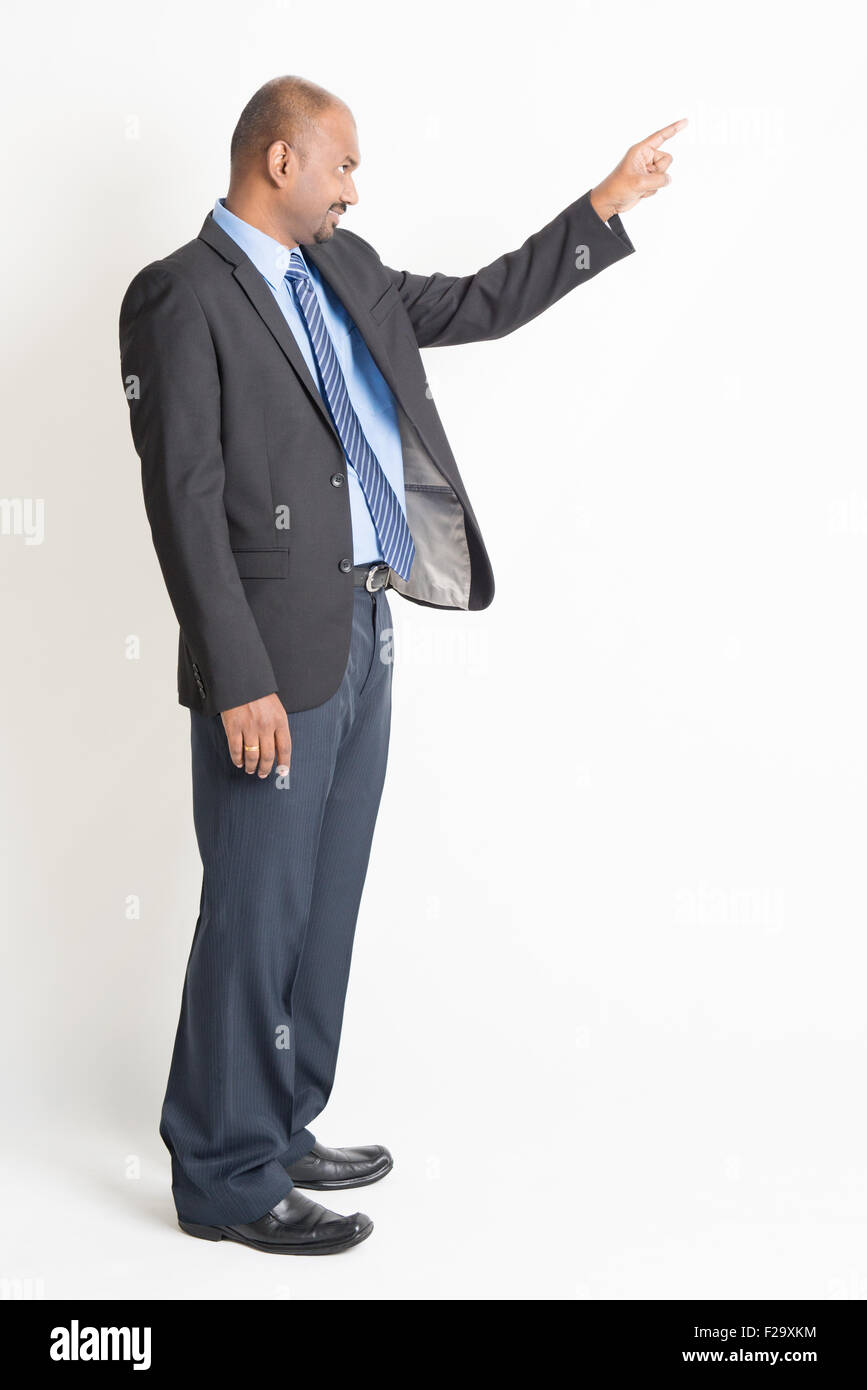 Side view full body mature Indian business man pointing to blank space ...