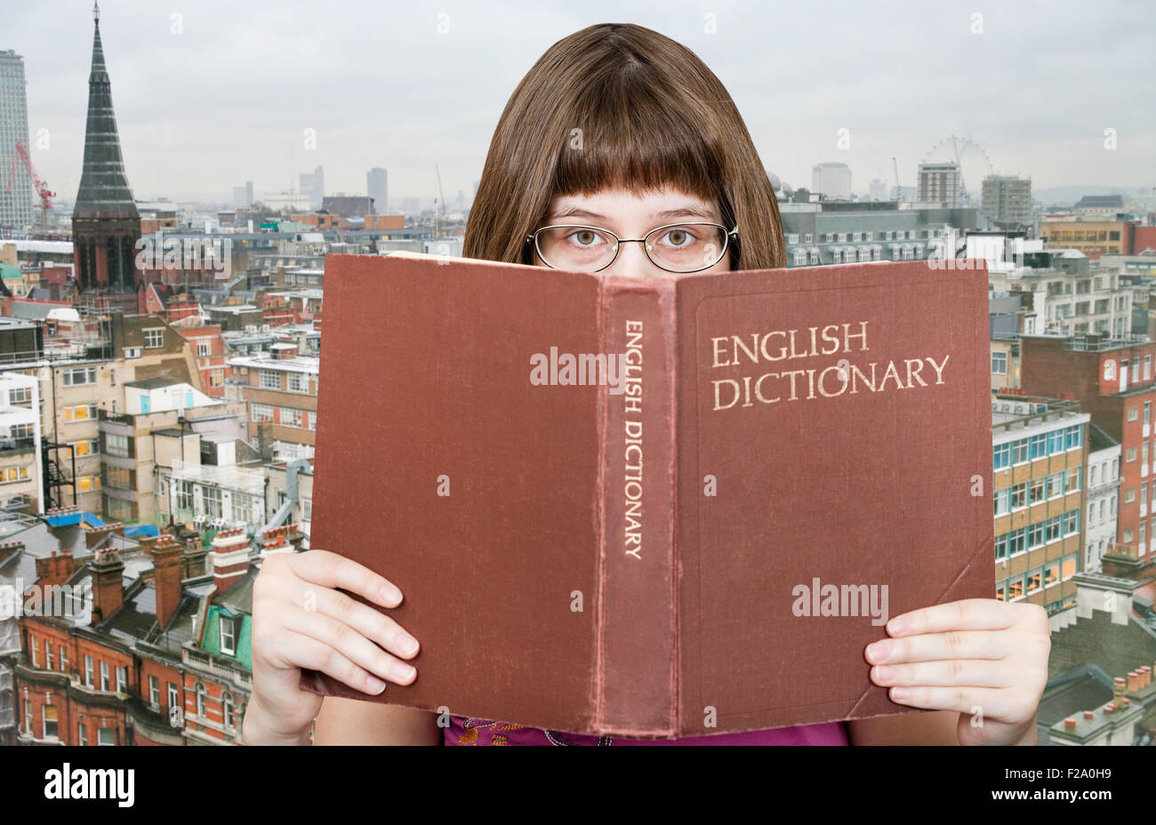 girl with spectacles looks over English Dictionary book and London ...