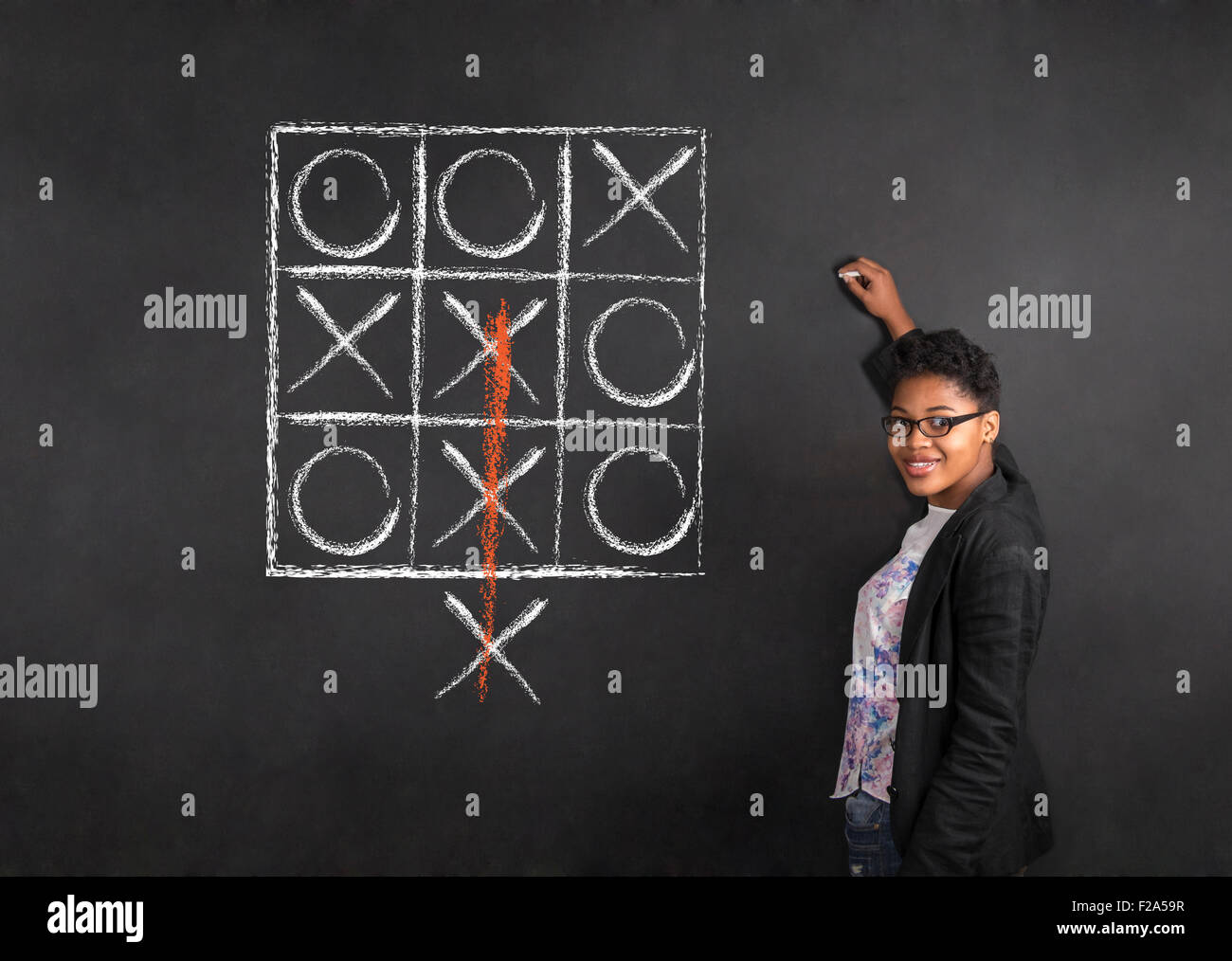 South African or African American woman teacher writing tic tac toe on ...