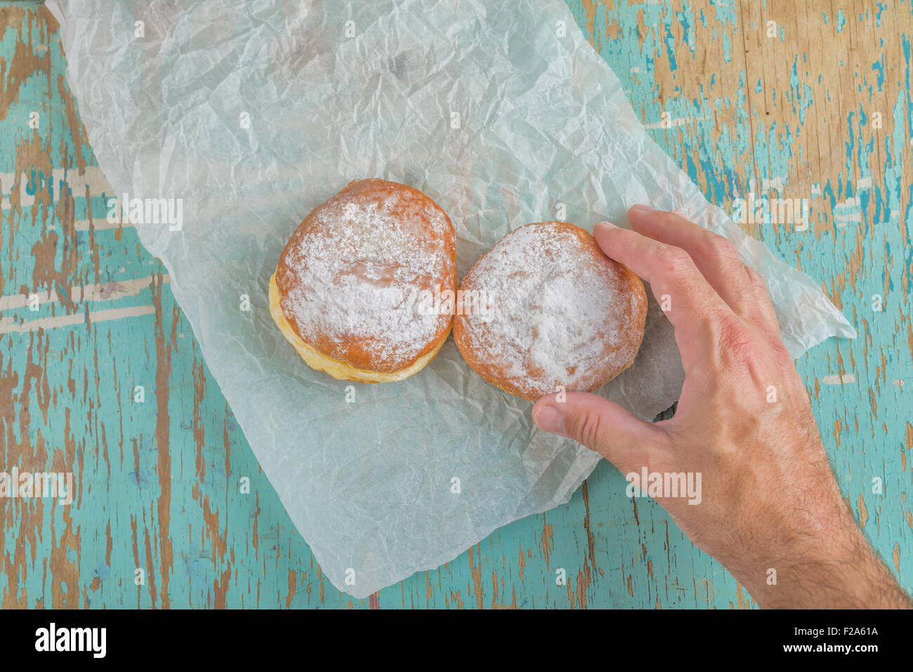 Male hand reaches and picking sweet sugary donut from rustic wooden ...