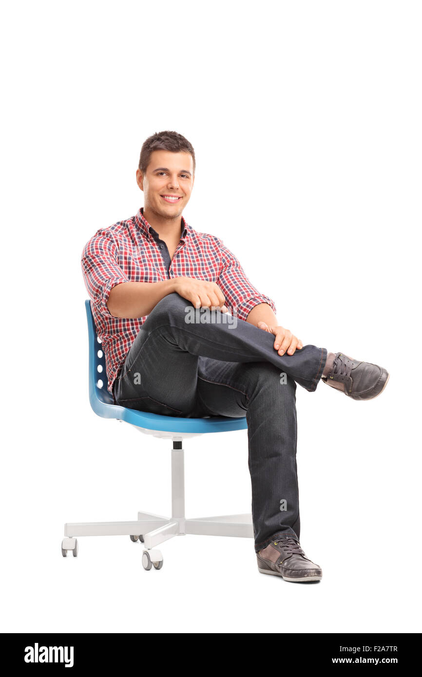 Vertical studio shot of a relaxed young man sitting on a chair and ...