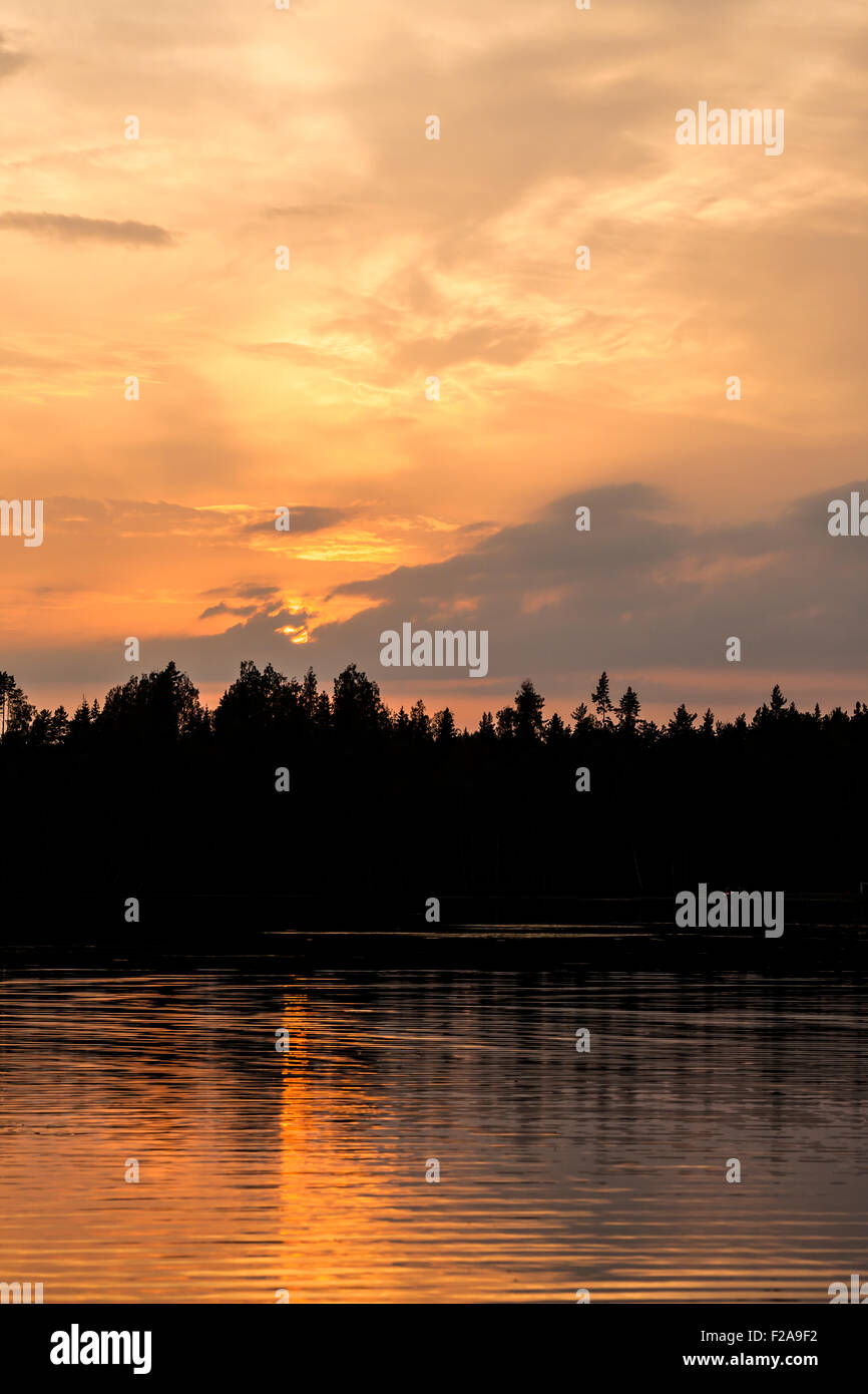 Fiery sunset at lakeside and silhouette forest Stock Photo - Alamy