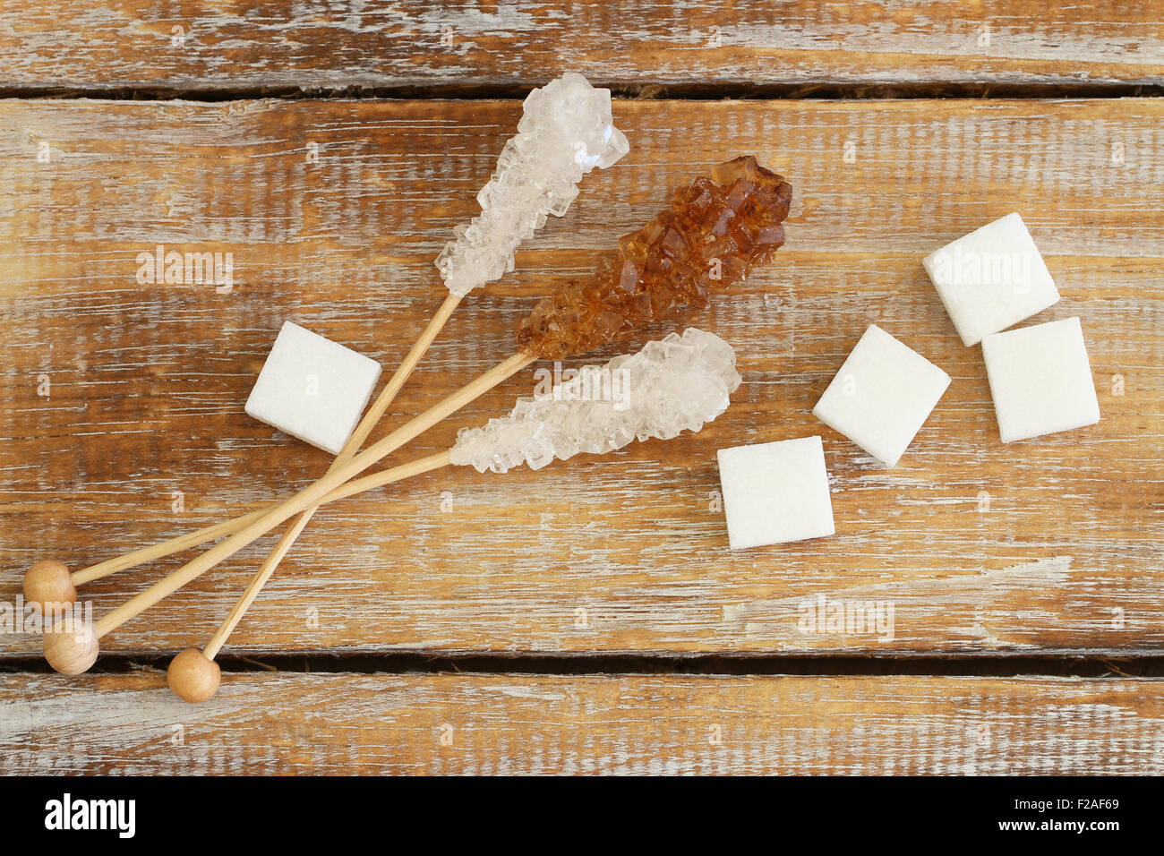 White sugar cubes and white and brown sugar sticks on rustic wooden ...