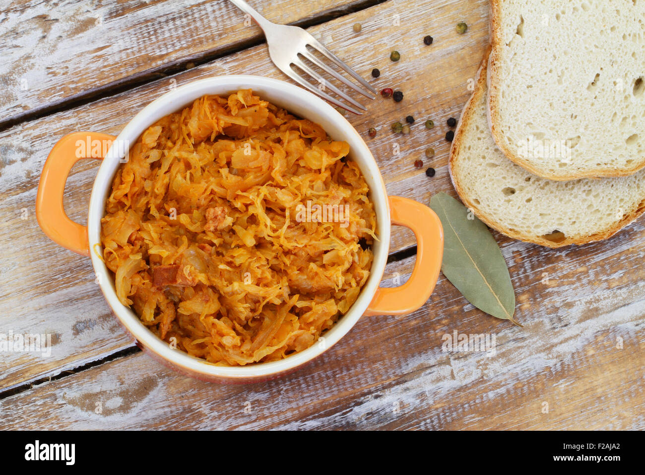 Polish bigos in saucepan and bread roll on rustic wooden surface Stock ...