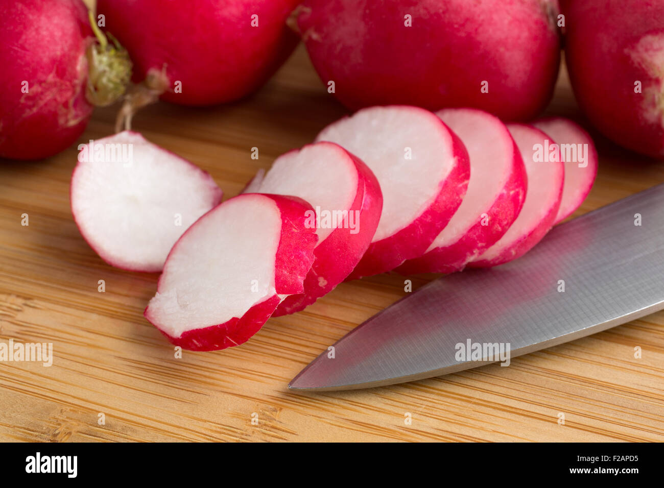 A close view of a sliced radish on a cutting board with a knife plus ...