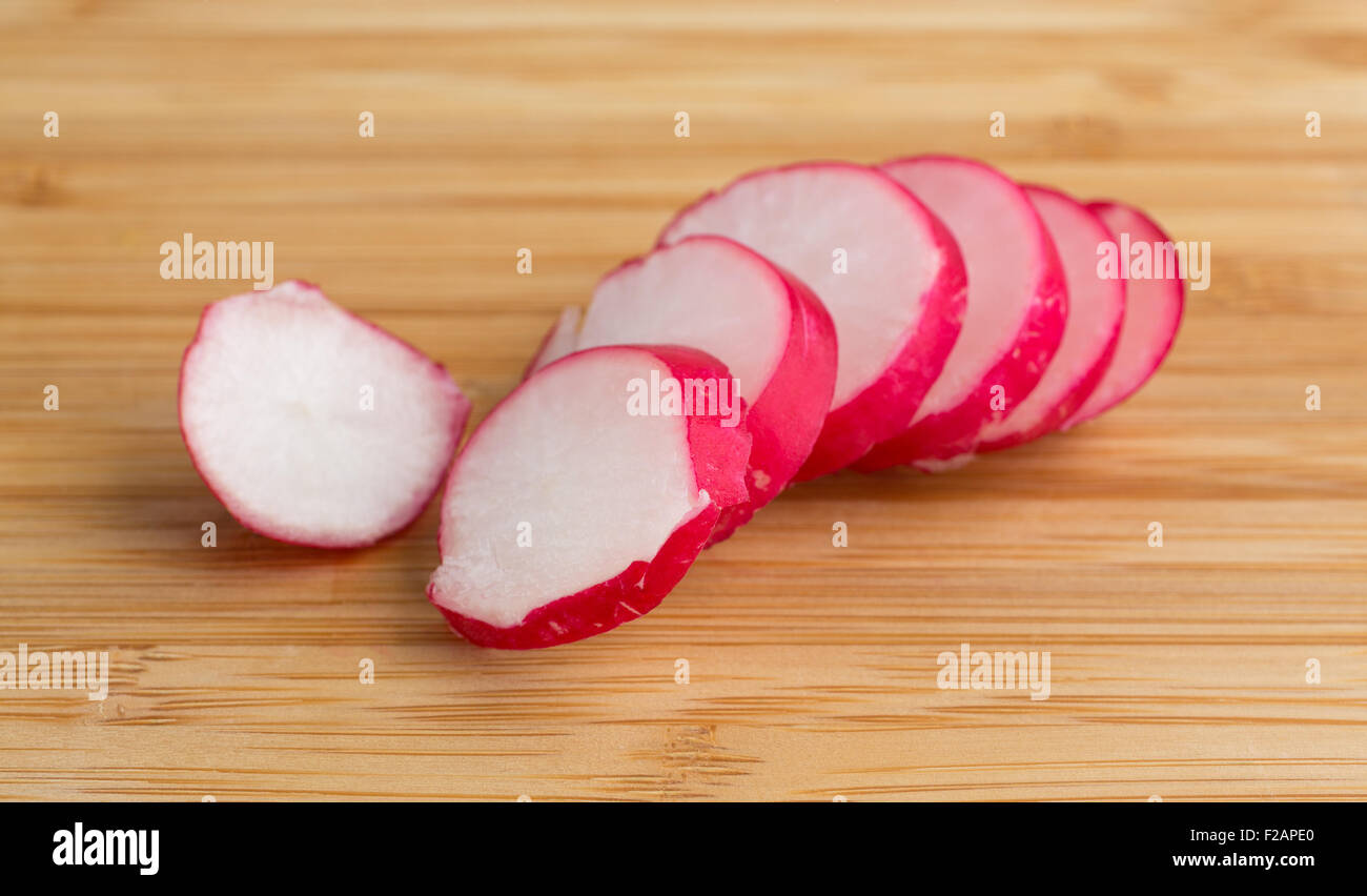 A sliced radish on a cutting board with a knife illuminated with ...