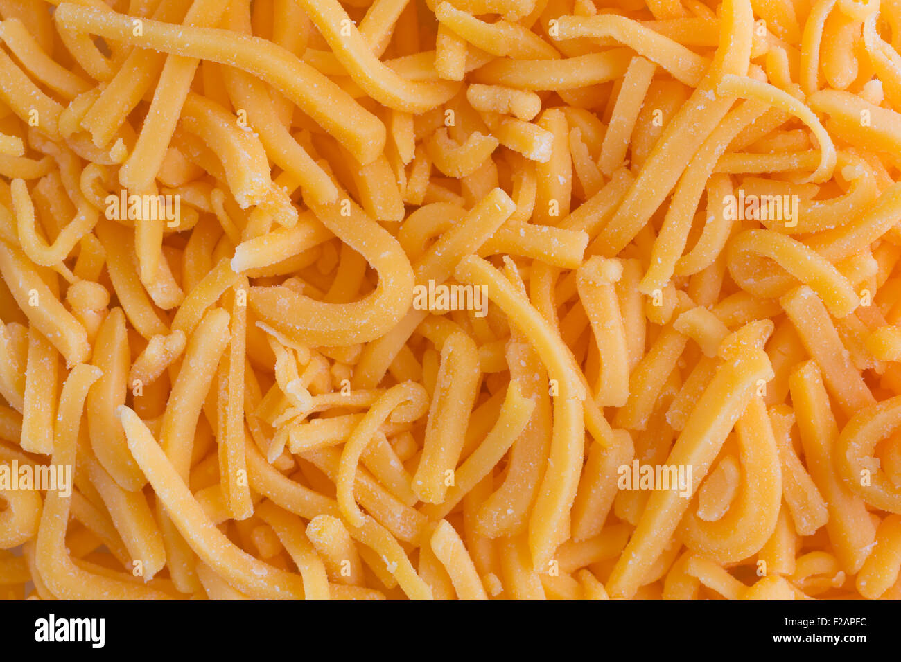 A very close view of shredded sharp cheddar cheese illuminated with ...
