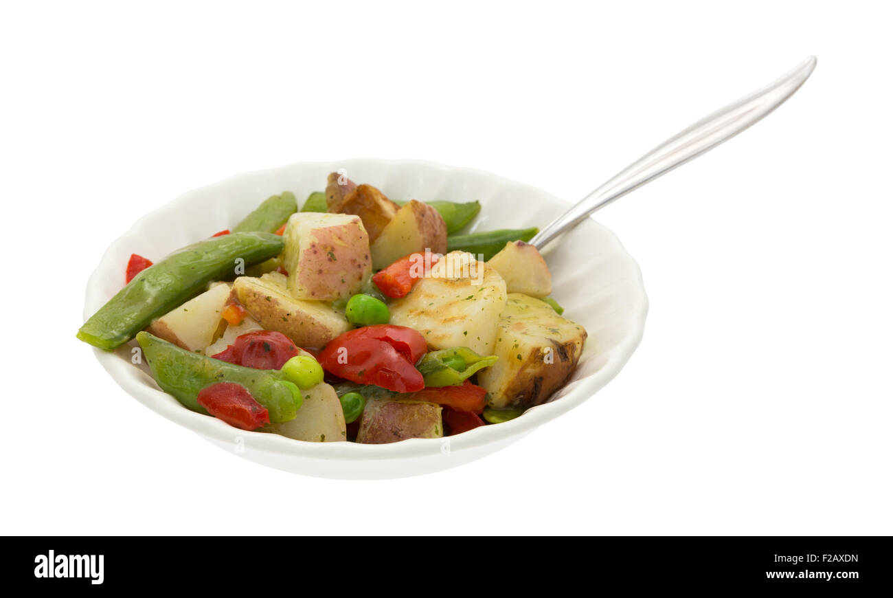 A bowl of roasted potatoes, snap peas and red peppers in a garlic sauce ...