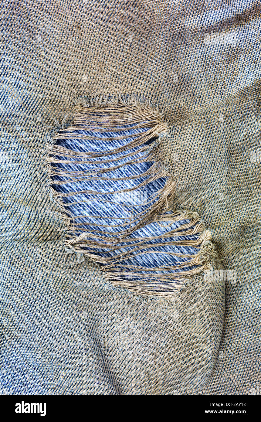Close view of a ragged hole in muddy worn blue jeans Stock Photo - Alamy