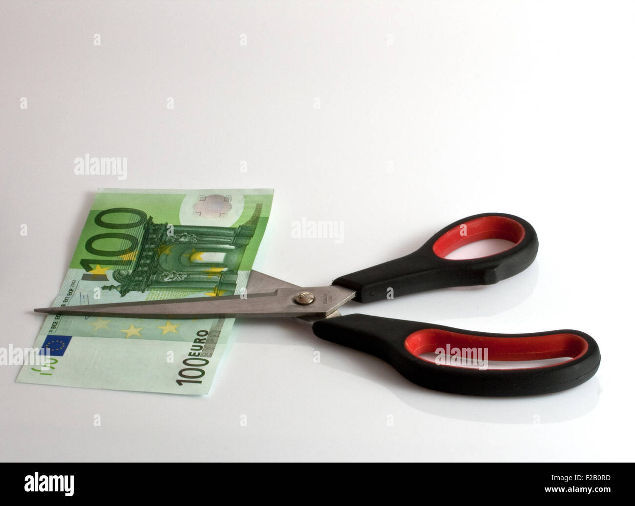 Scissors cutting the money, white background Stock Photo - Alamy